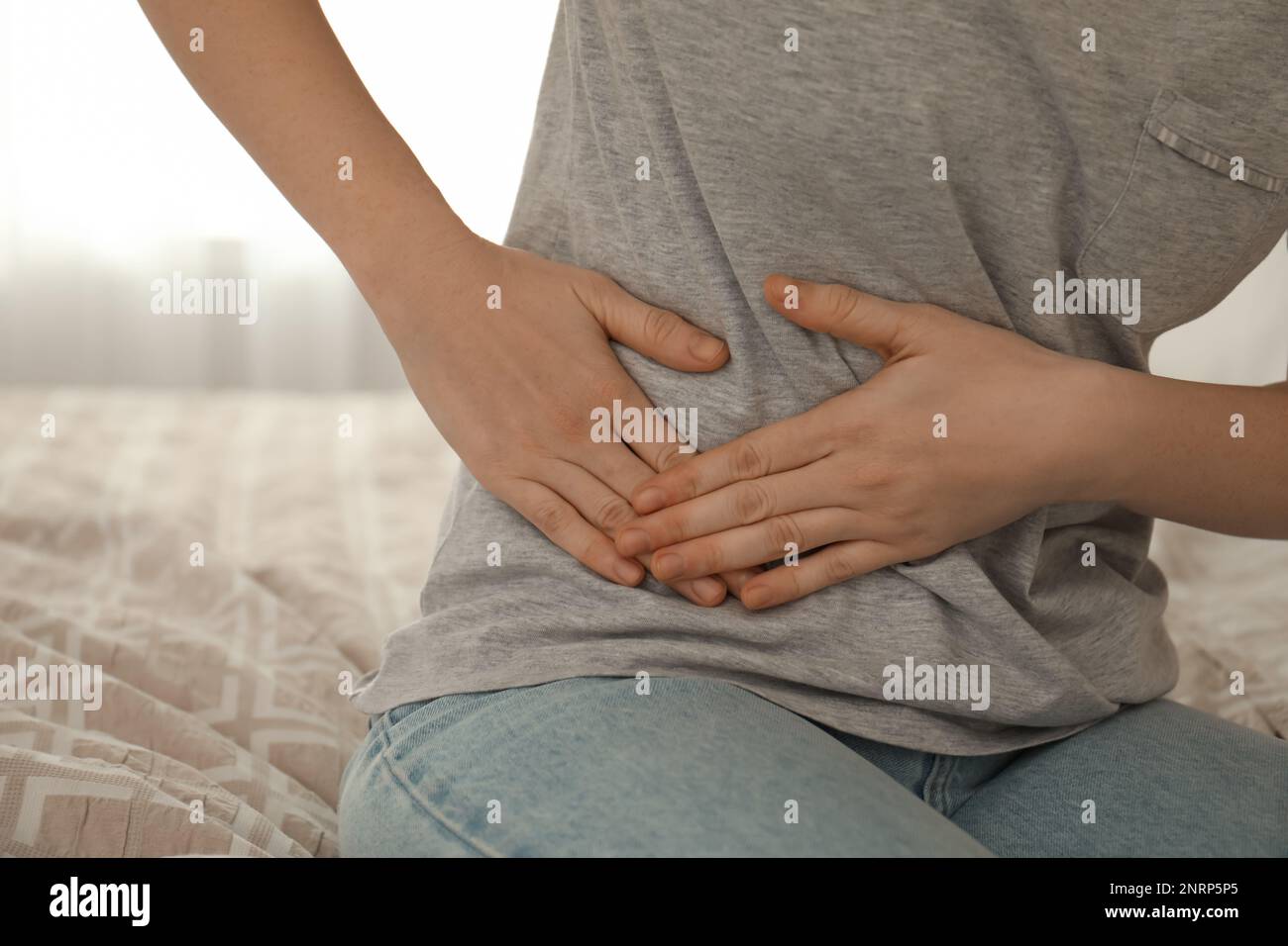 Woman suffering from appendicitis inflammation on bed at home, closeup ...
