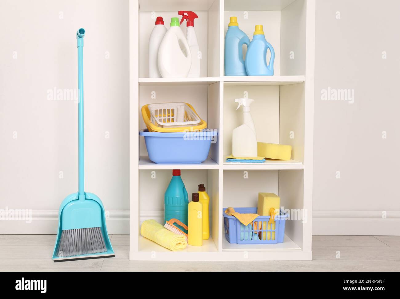 Shelving unit with detergents and cleaning tools near white wall ...