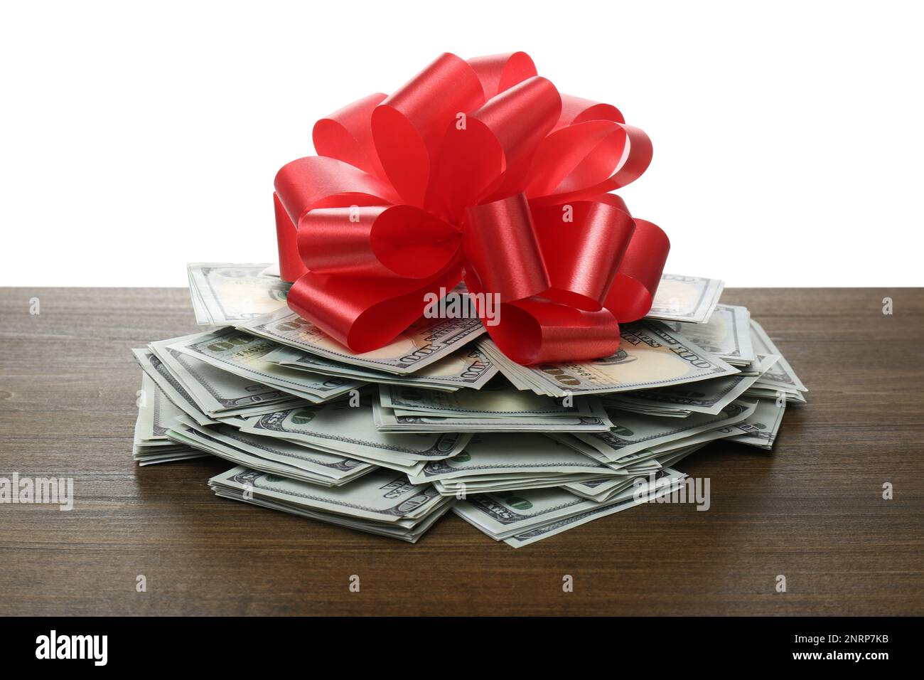 Pile of dollar bills with red bow on wooden table against white ...