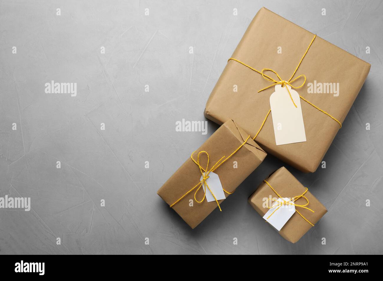 Parcels wrapped in kraft paper with tags on light grey table, flat lay ...
