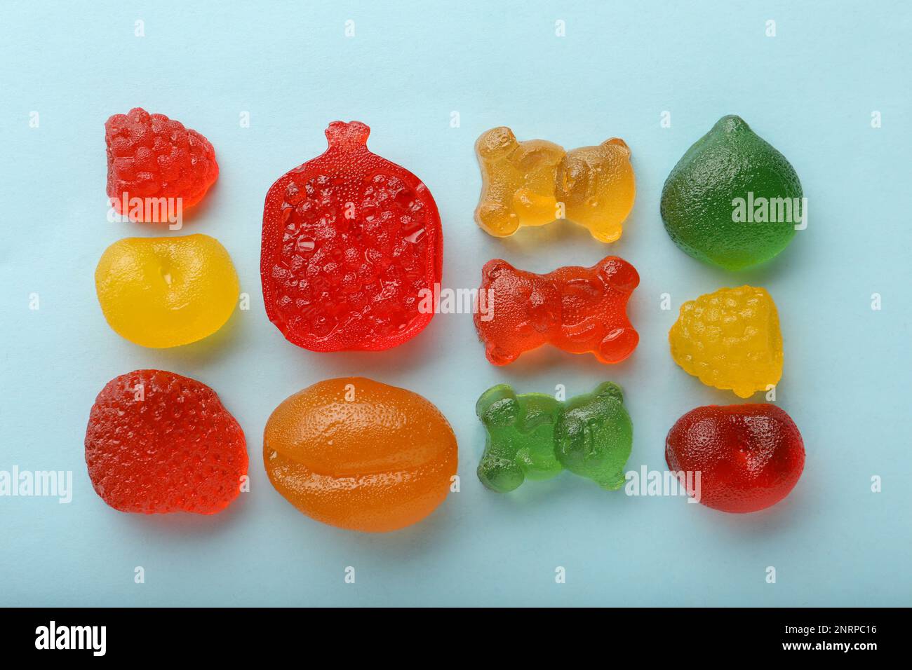 Mix of different delicious gummy candies on light blue background, flat ...