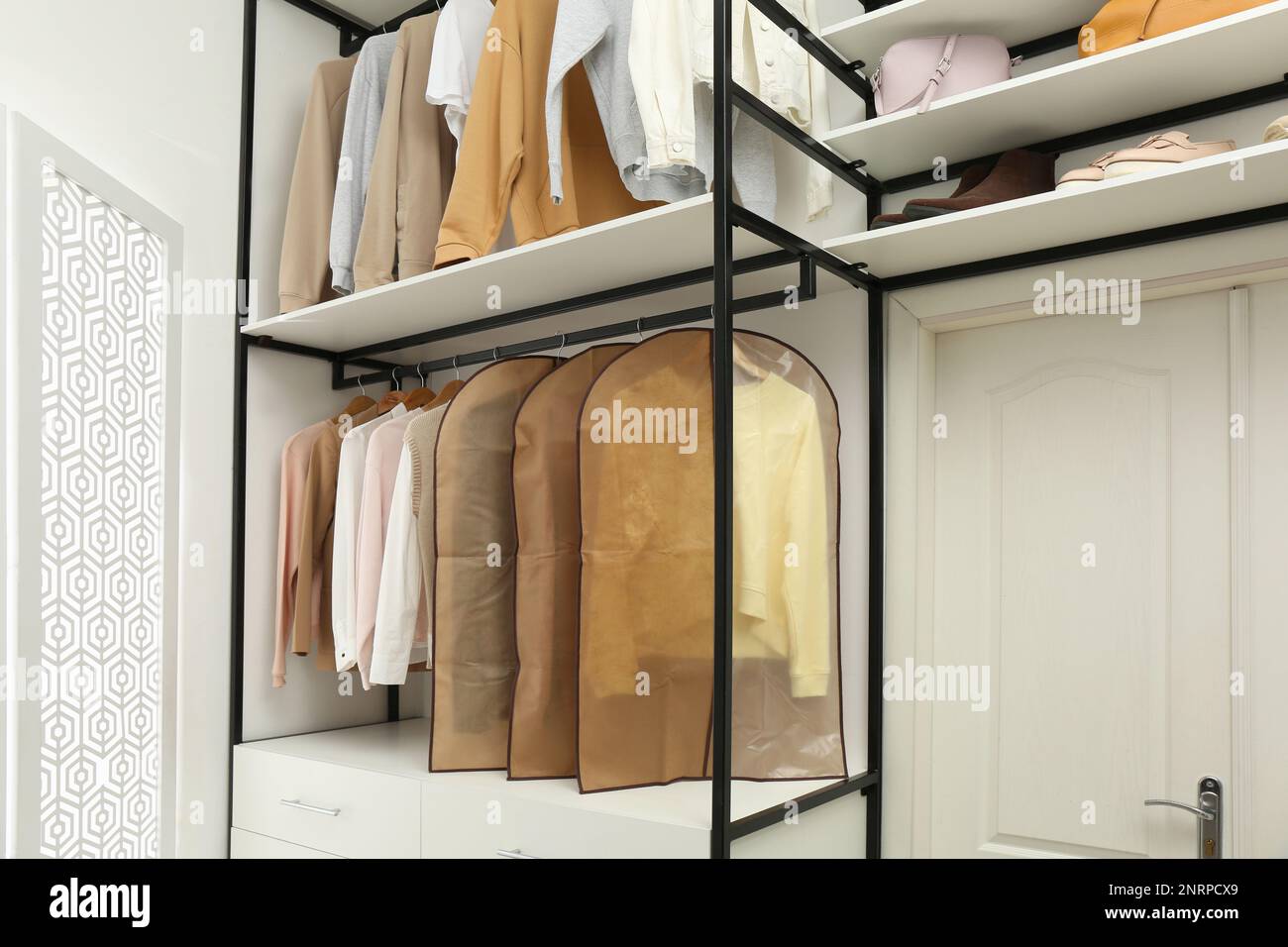 Garment bags with clothes on rack in dressing room Stock Photo - Alamy