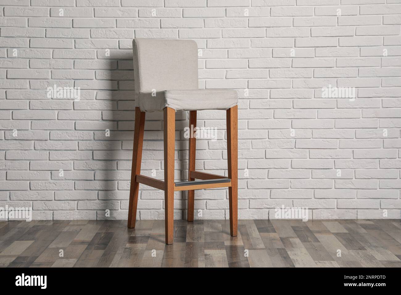 Stylish bar stool near white brick wall indoors Stock Photo - Alamy