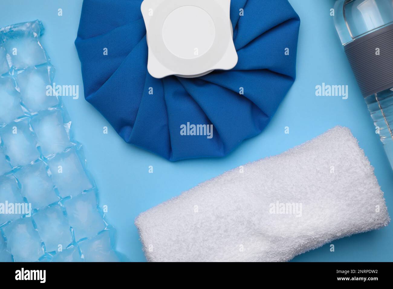 Bottle of water, cold compress, ice pack and towel on light blue ...