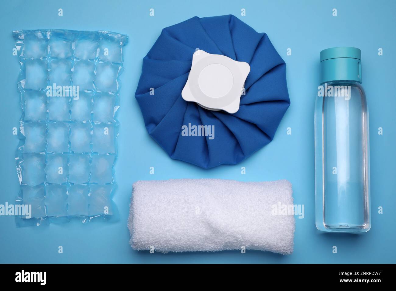 Bottle of water, cold compress, ice pack and towel on light blue ...