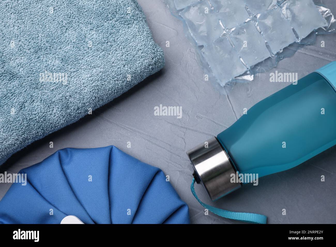 Bottle of water, cold compress, ice pack and towel on grey background ...