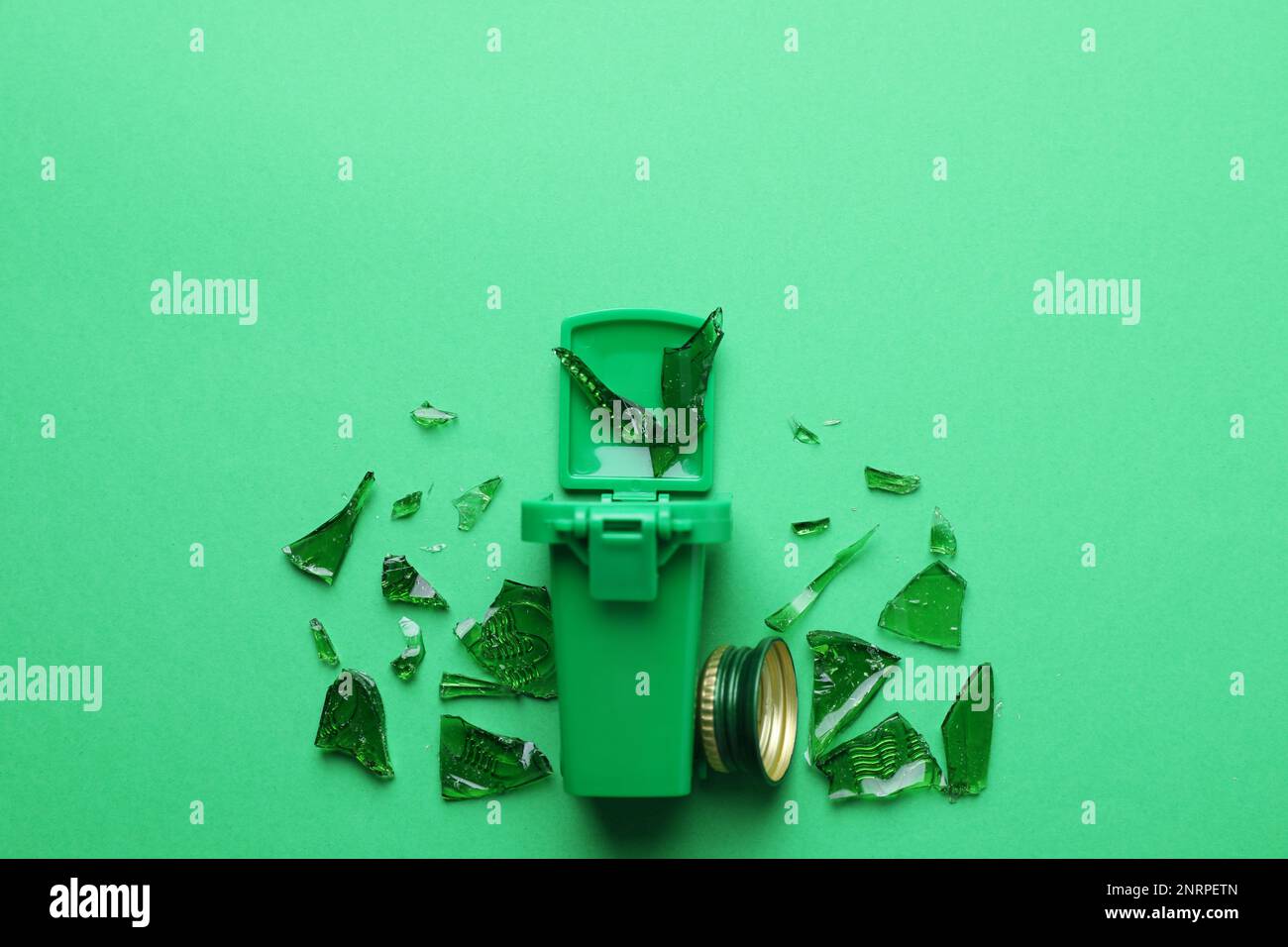 Mini recycling bin, cap and glass shatters on green background, flat ...