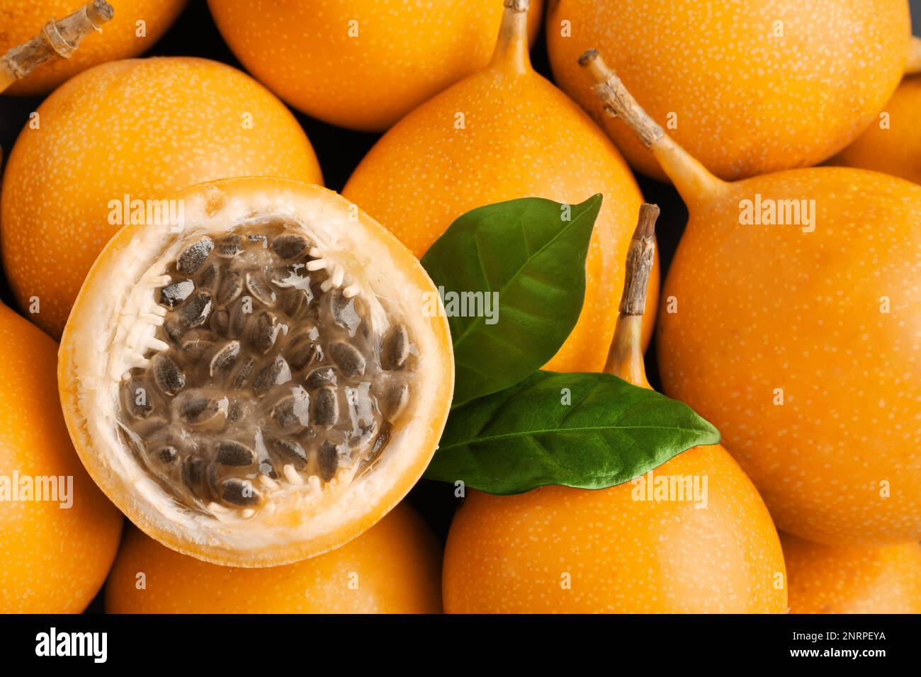 Delicious whole and cut granadillas with leaves as background, top view ...