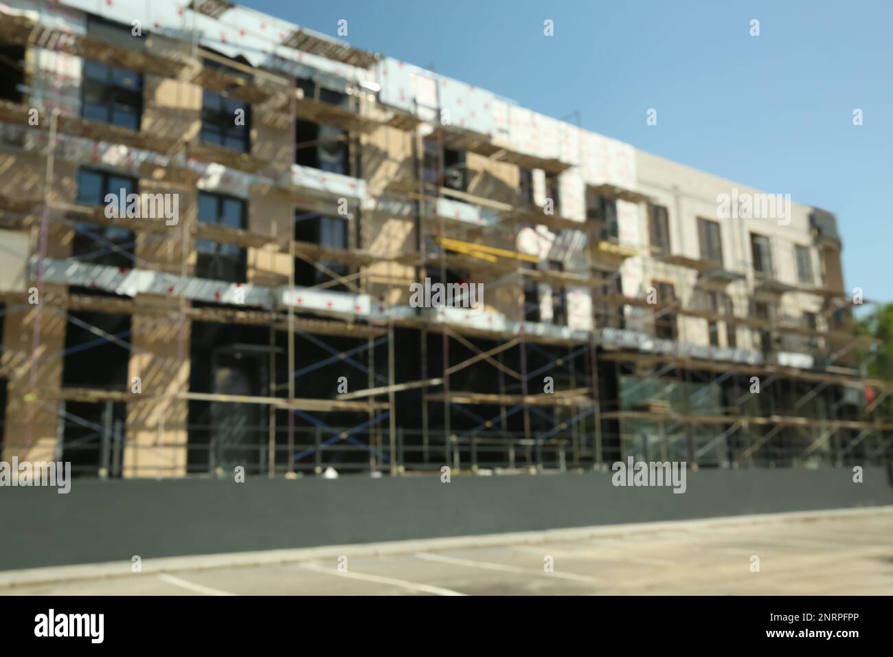 Blurred view of unfinished building with scaffolding against blue sky ...