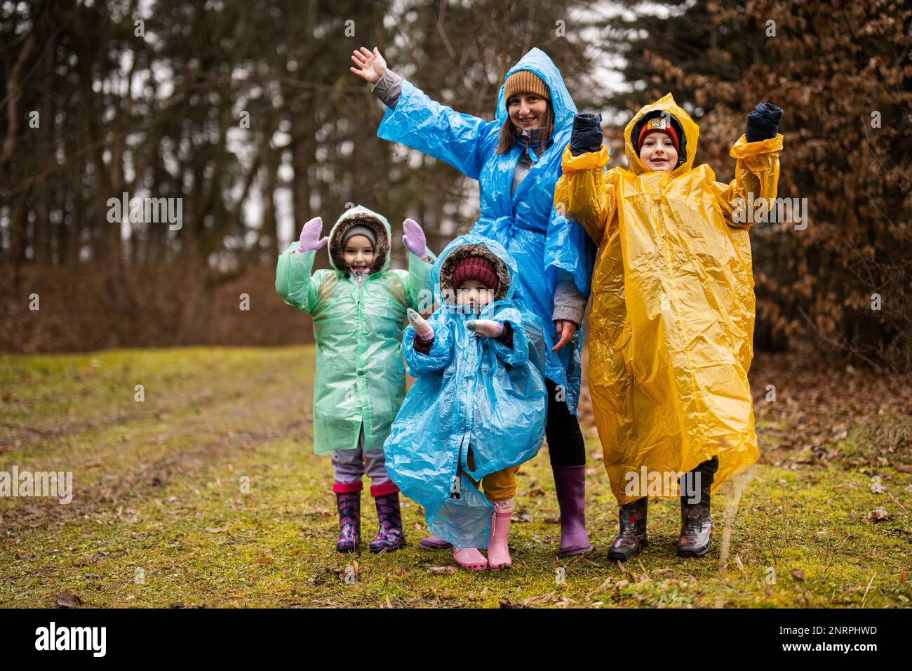 Mother and three children in the forest after rain in raincoats ...