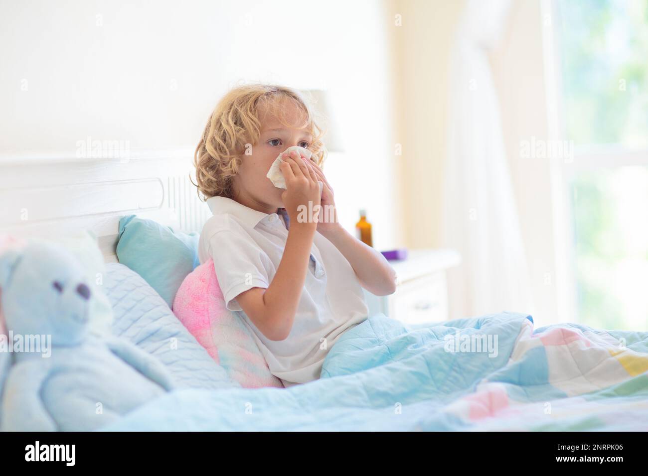 Sick child in bed. Mother checking on unwell kid. Little boy having fever feeling ill. Mom with ...