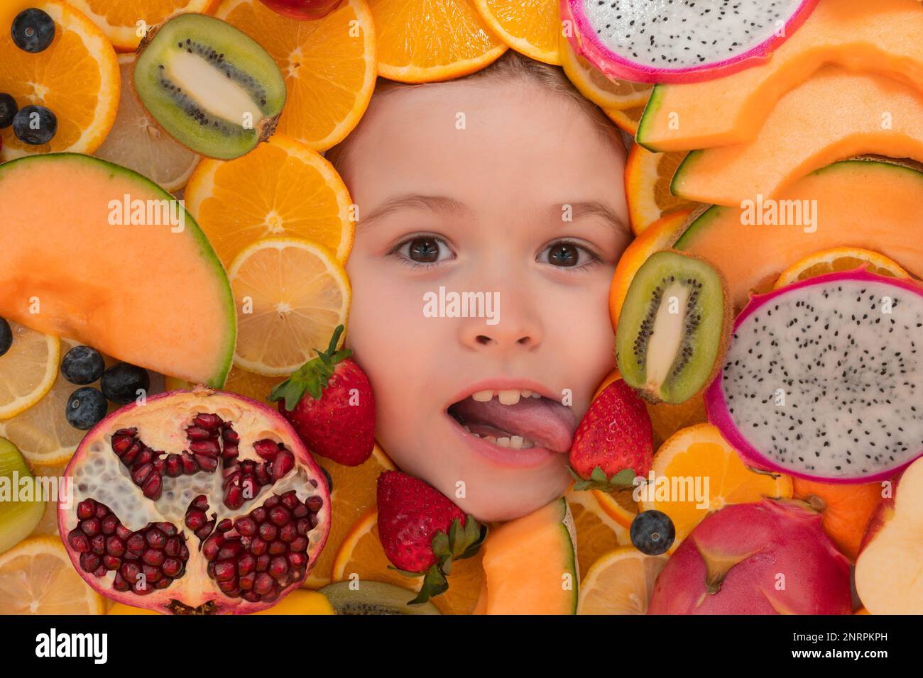 Funny licking fruit. Kid smiling face portrait surrounded by fruits ...