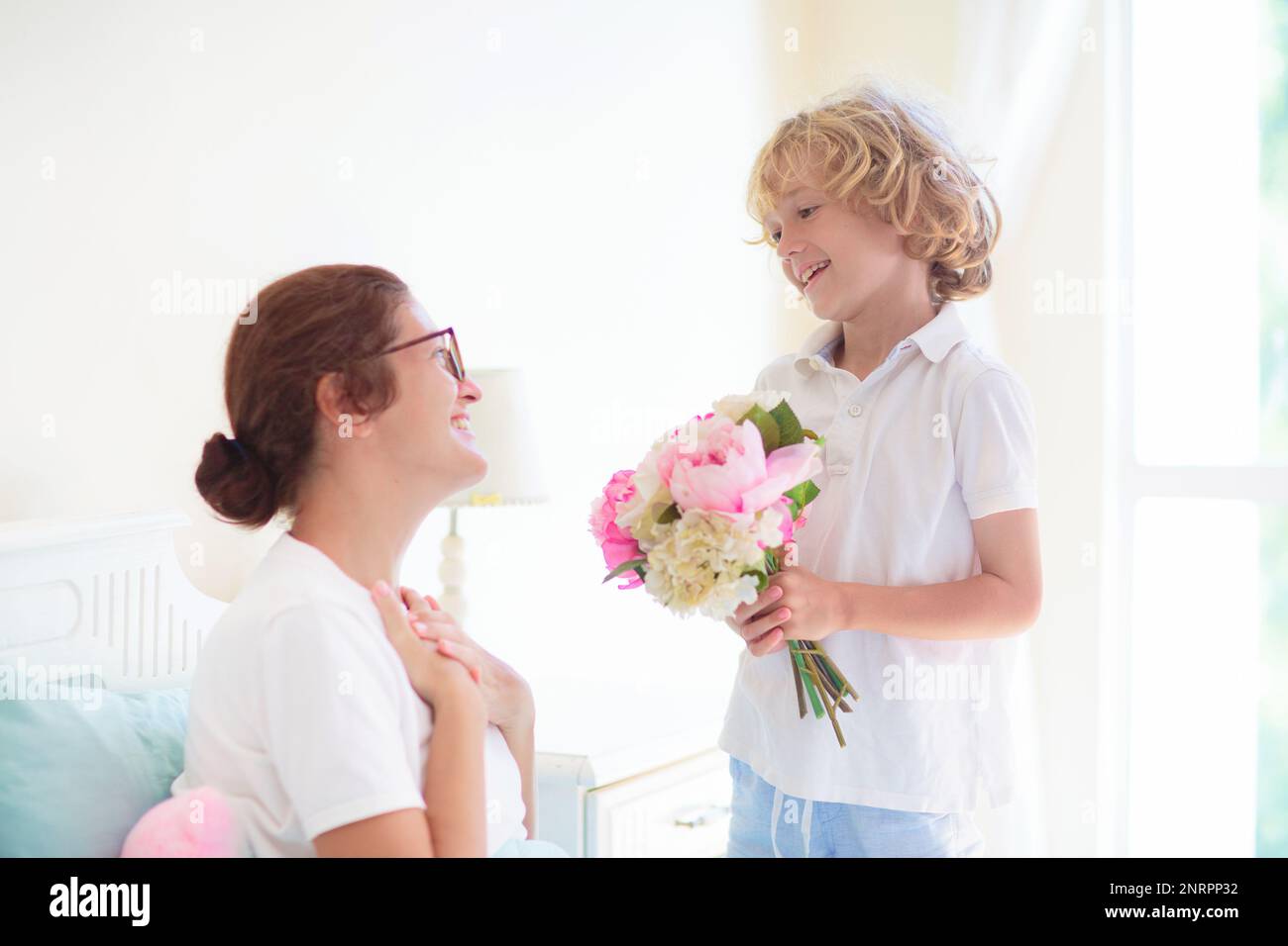 Child giving mom present in bed. Mother’s Day morning gift. Little boy ...
