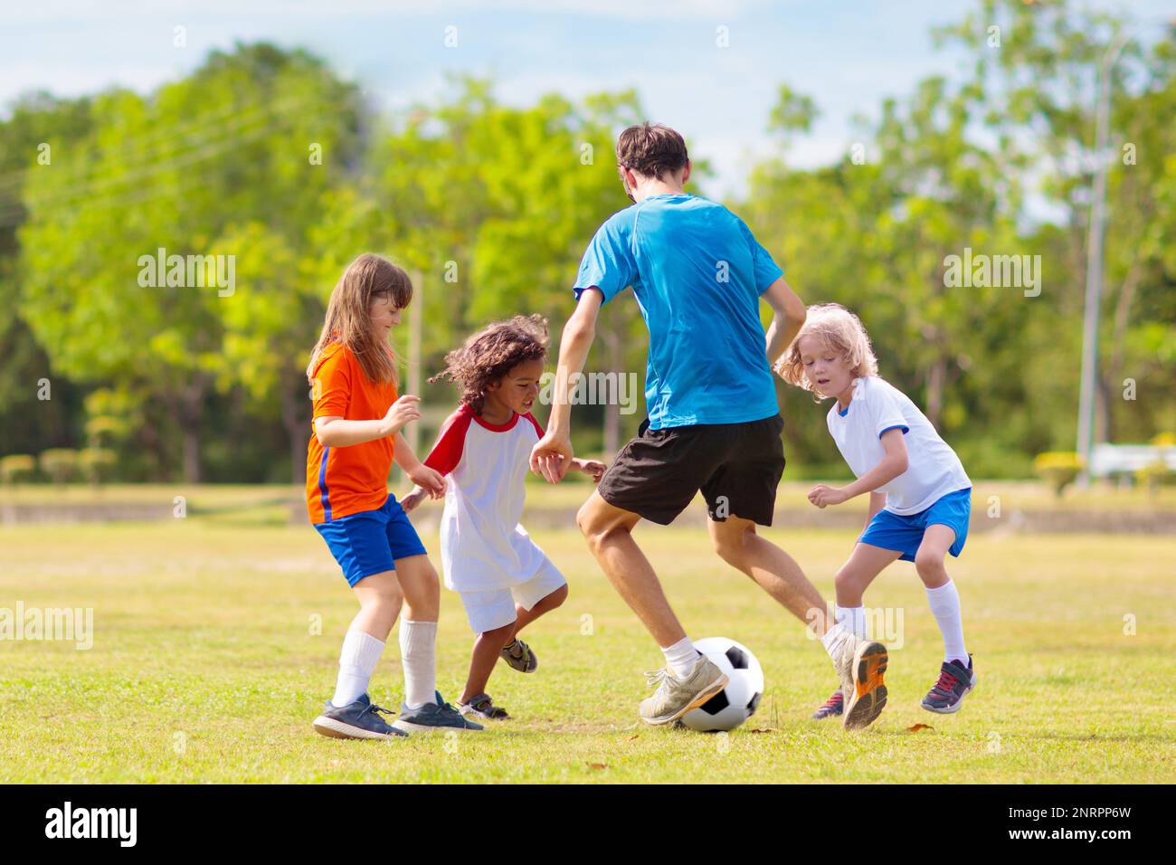 Kids play football on outdoor field. Children score a goal at soccer ...