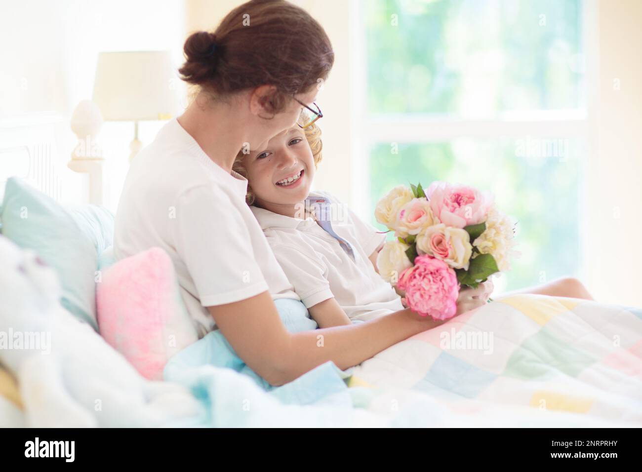 Child giving mom present in bed. Mother’s Day morning gift. Little boy ...