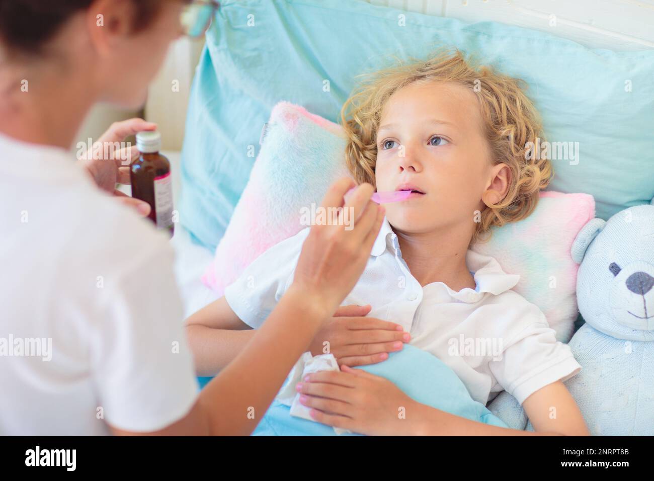 Sick child in bed. Mother checking on unwell kid. Little boy having fever feeling ill. Mom with ...