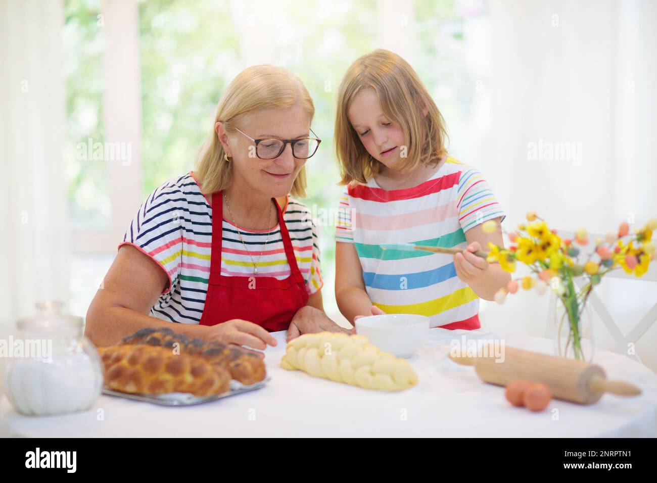Mom and child baking bread. Grandmother and little girl bake challah ...