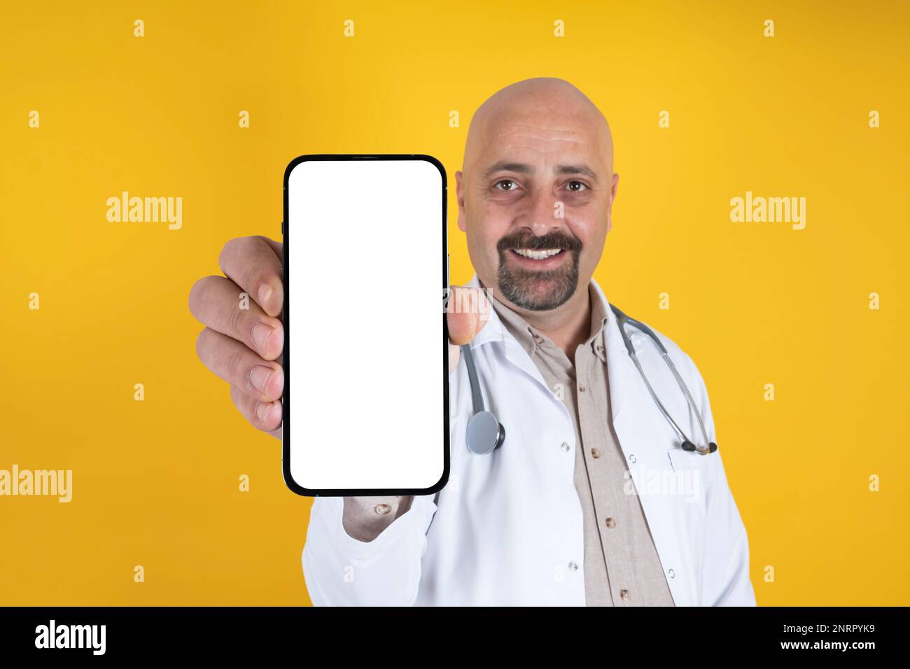 Smiling positive caucasian doctor showing mobile phone mock up. Wearing ...