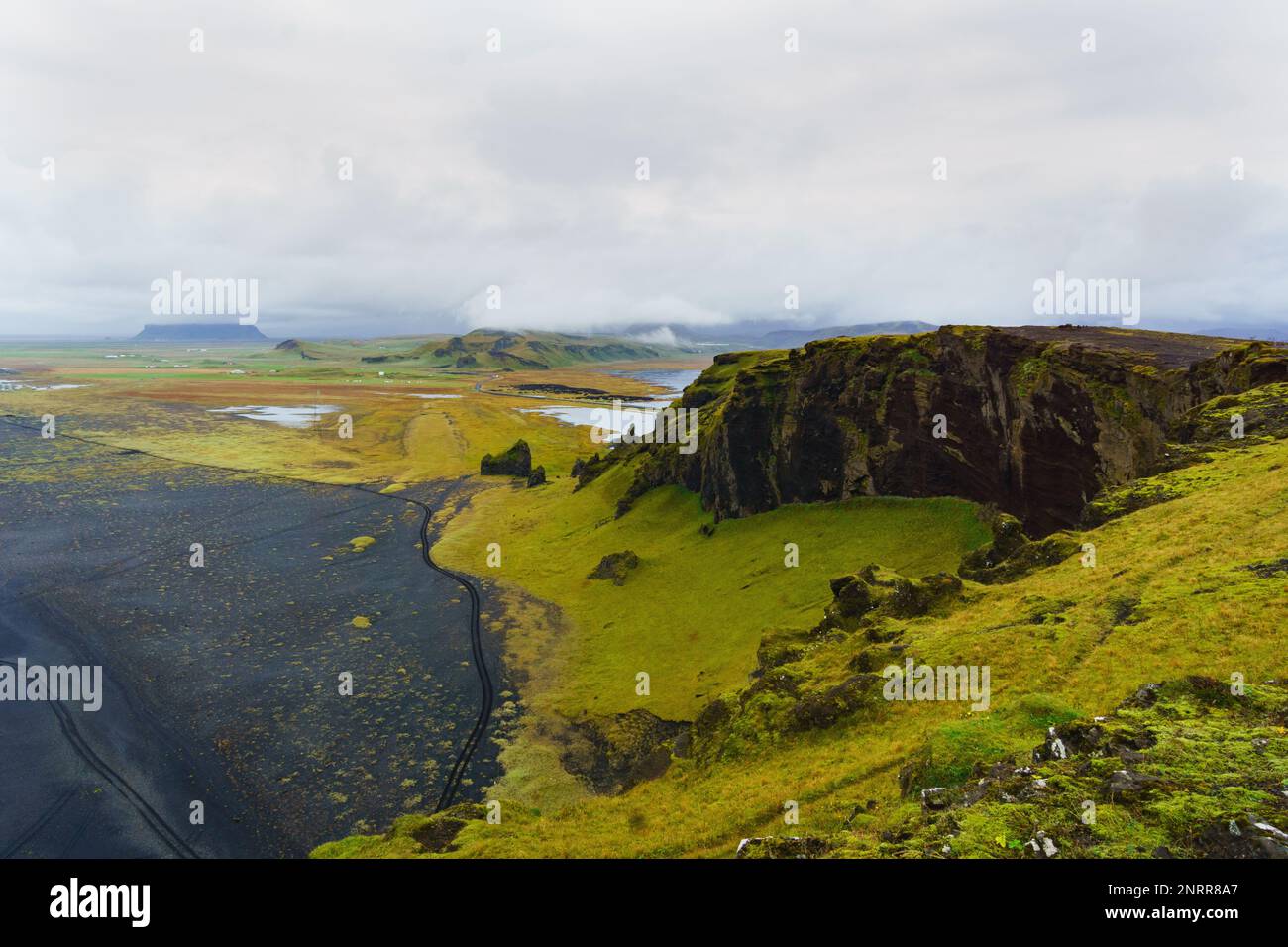 Southern Iceland, Vik. View on cliffs, green valley and black sands ...