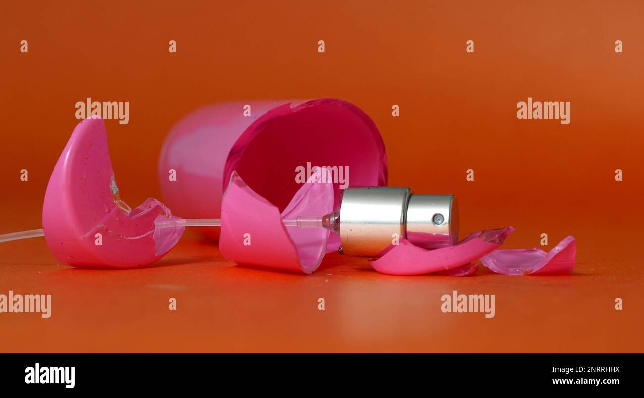 Broken pink perfume bottle on orange background Stock Photo - Alamy