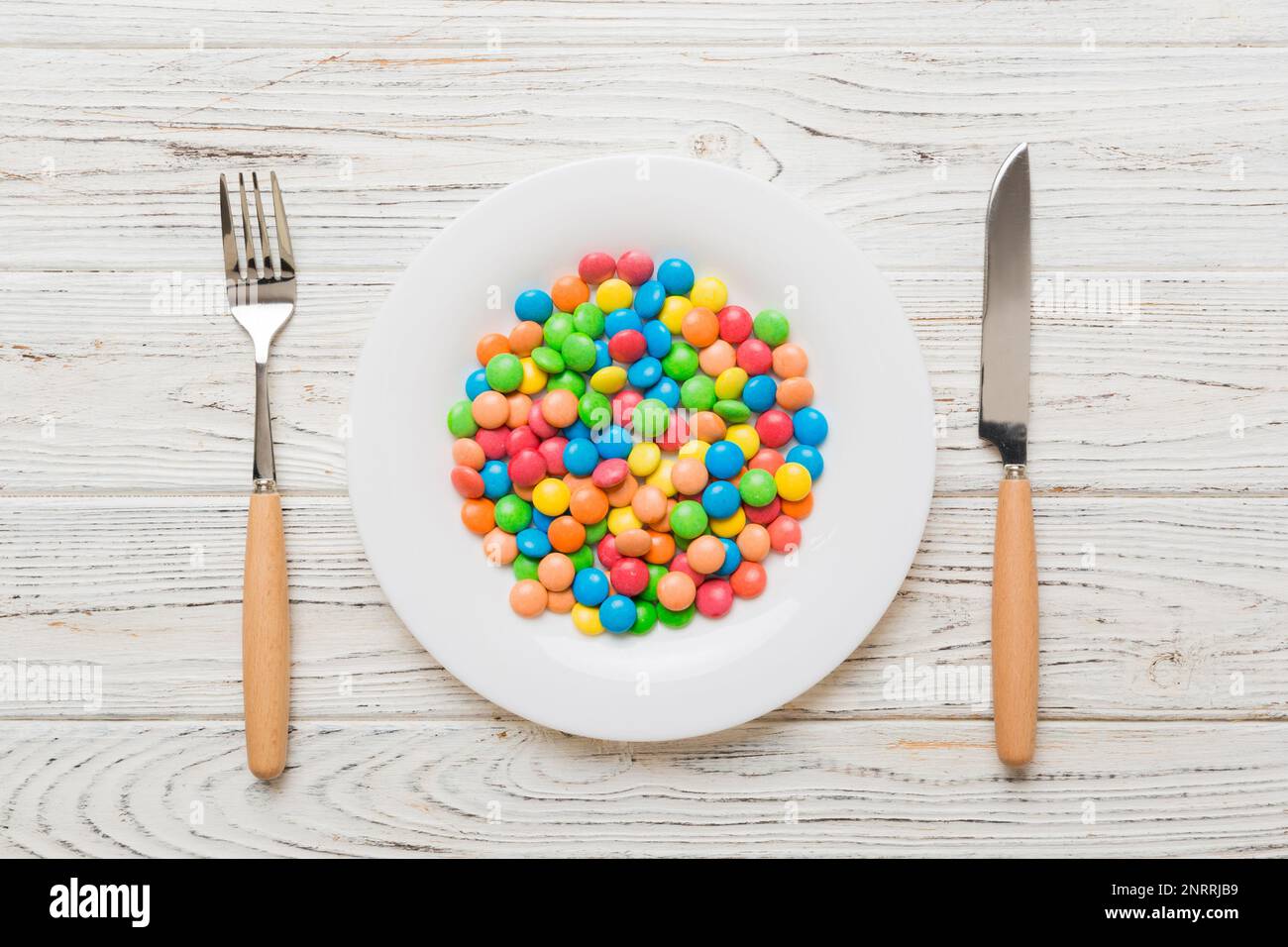 cutlery on table and sweet plate of candy. Health and obesity concept ...