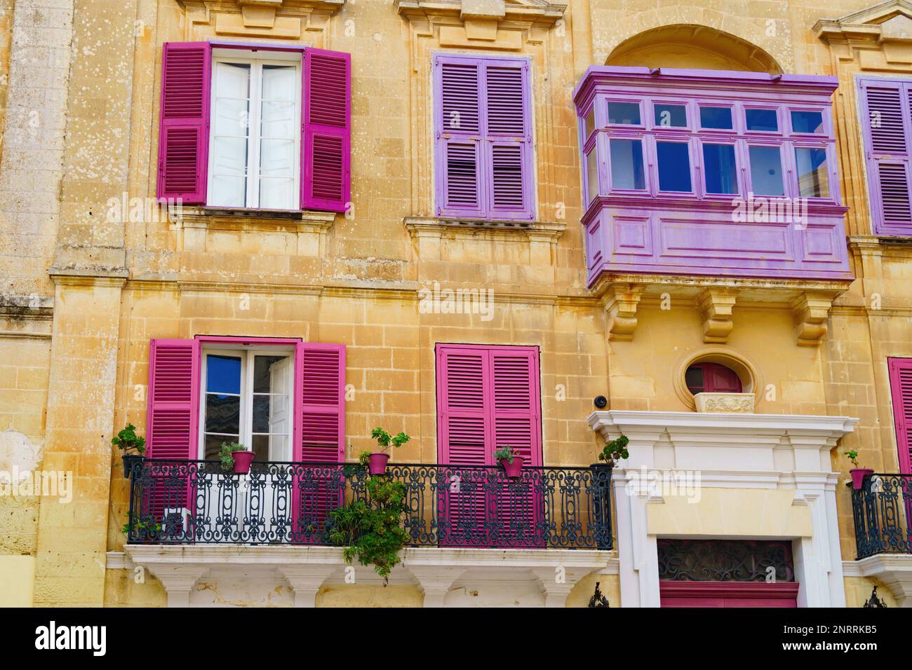Facade of the house with purple and pink maltese balconies, plants in ...