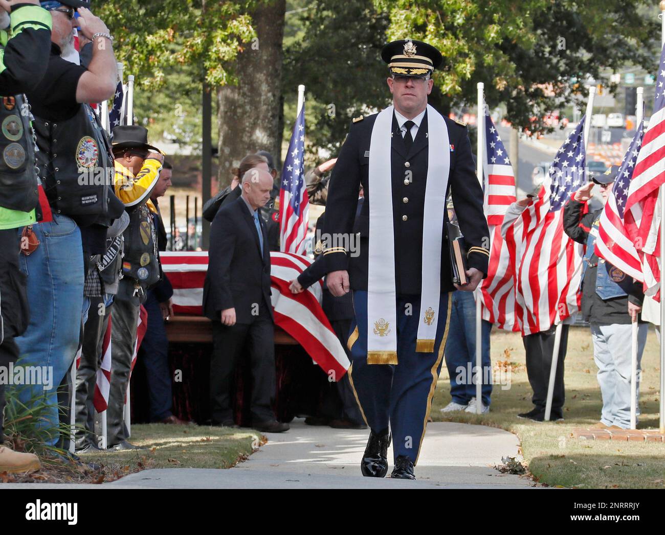 A Chaplain leads the procession as pall bearers carry the casket into ...