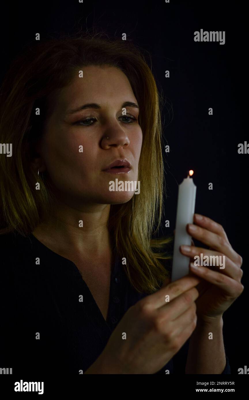 portrait of a beautiful blonde woman blowing out the flame of a candle ...