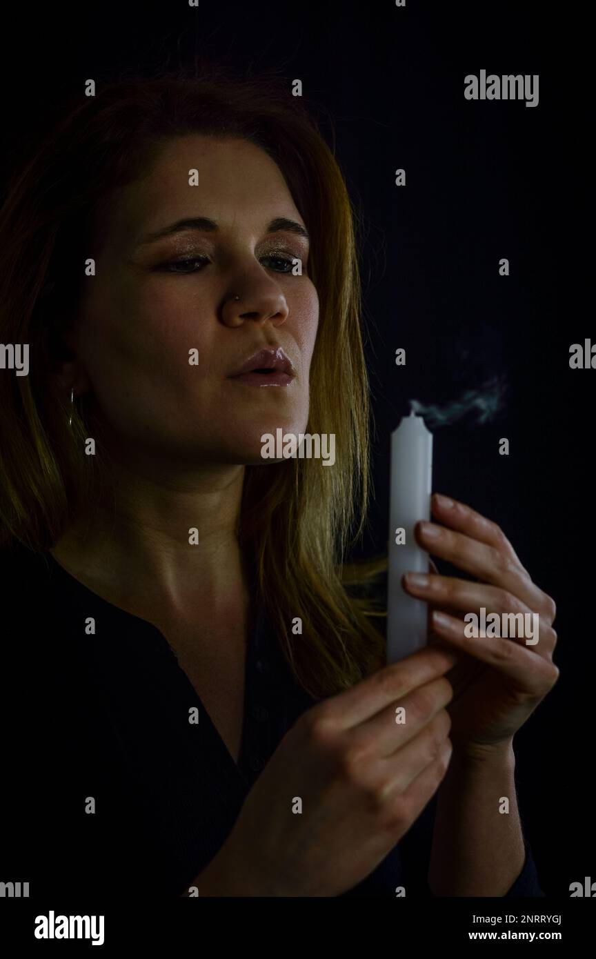 portrait of a beautiful blonde woman blowing out the flame of a candle ...
