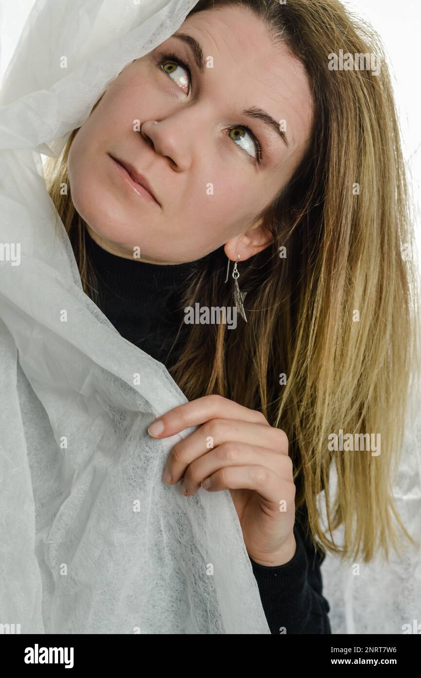 portrait of a beautiful blonde woman who is hiding behind a white ...