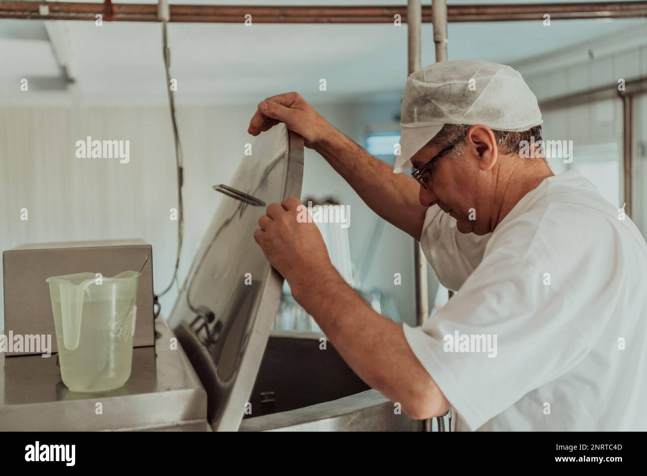Man mixing milk in the stainless tank during the fermentation process ...