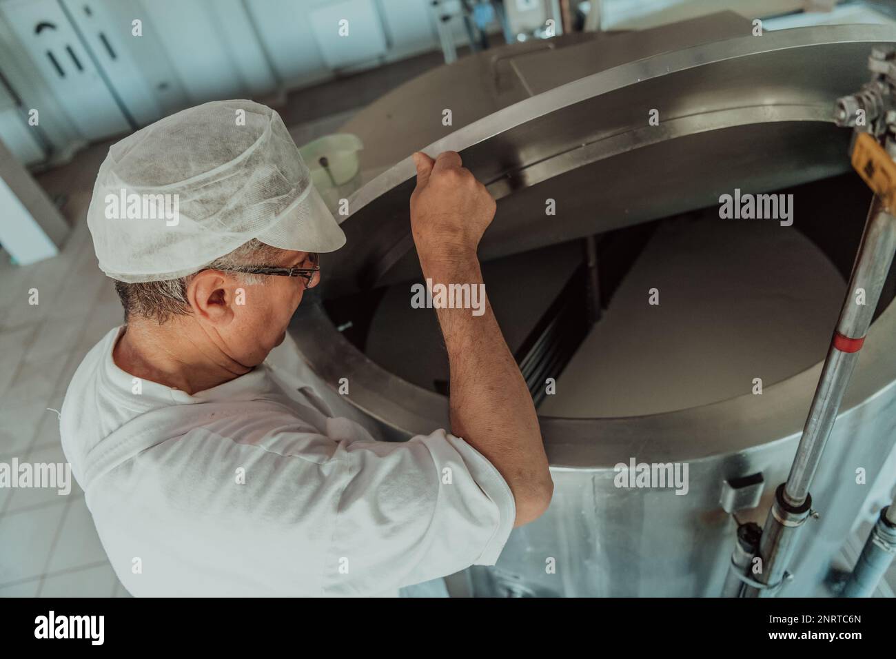 Man mixing milk in the stainless tank during the fermentation process ...