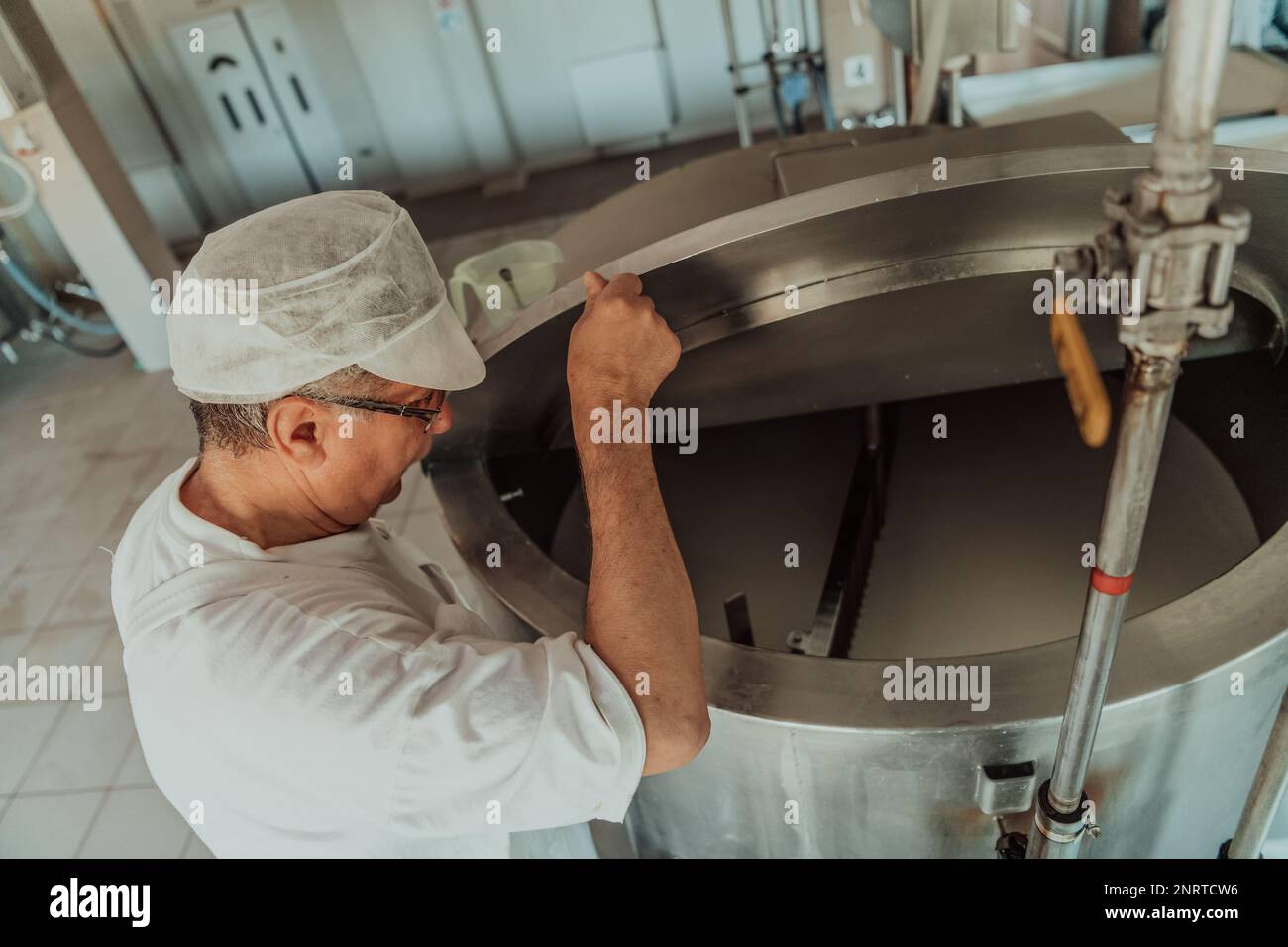 Man mixing milk in the stainless tank during the fermentation process ...