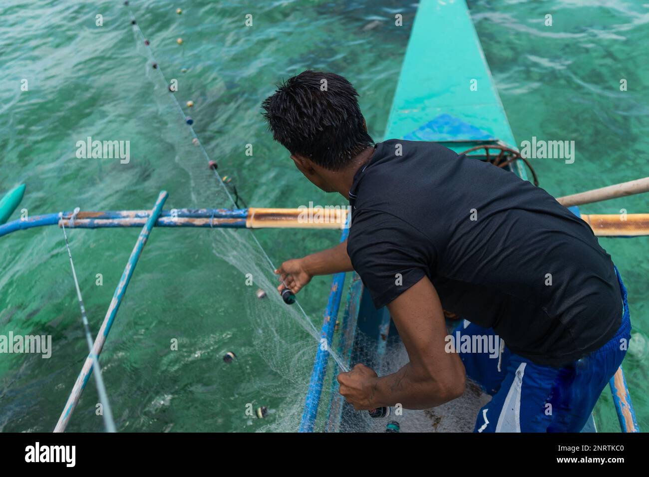 top view of young fisherman collecting his fishing net, philippines ...