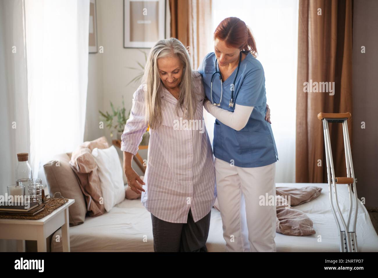 Nurse helping senior woman with walking after leg injury Stock Photo ...