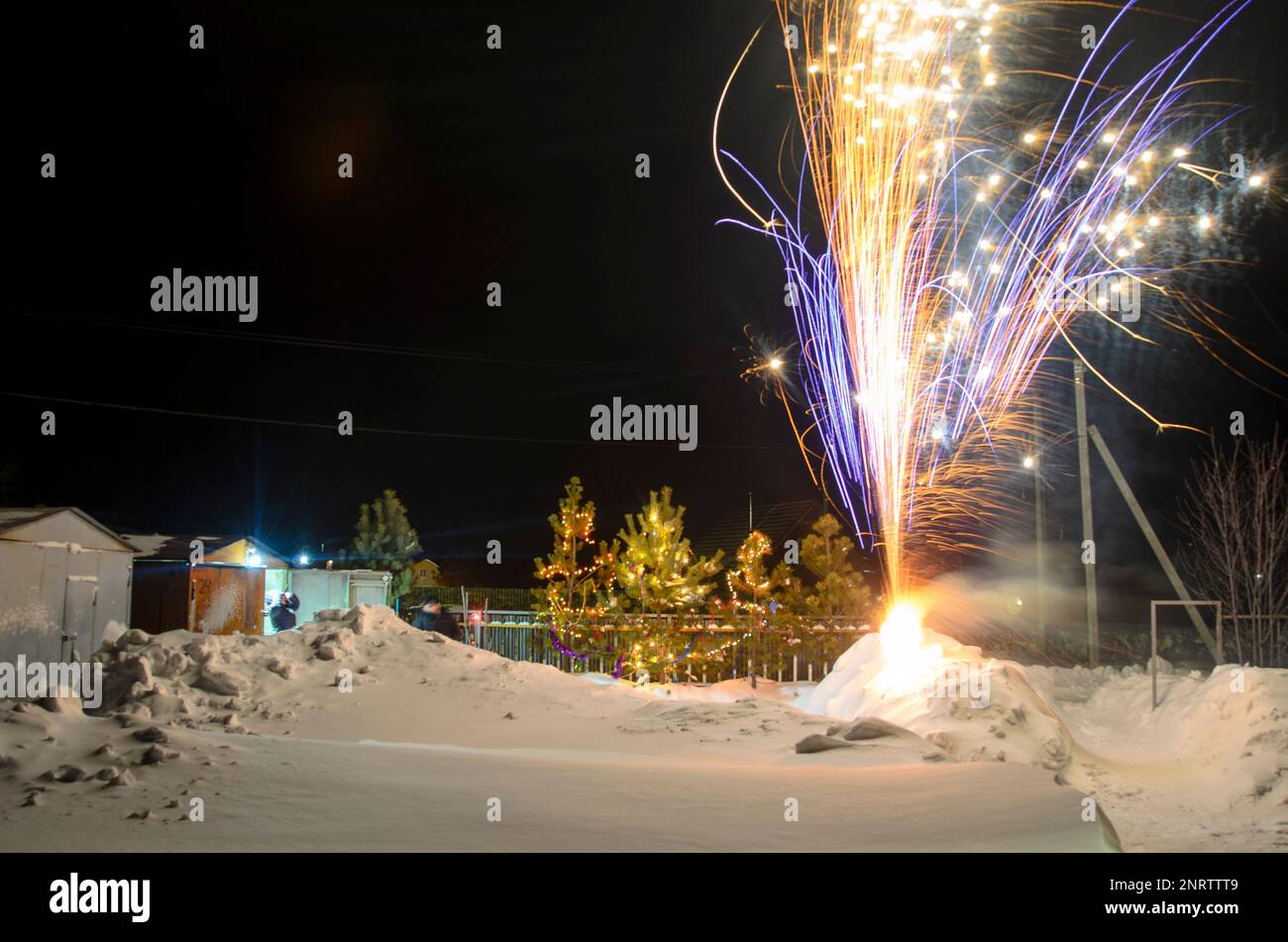 Bright flashes of fireworks in a garden plot in Siberia in winter with ...