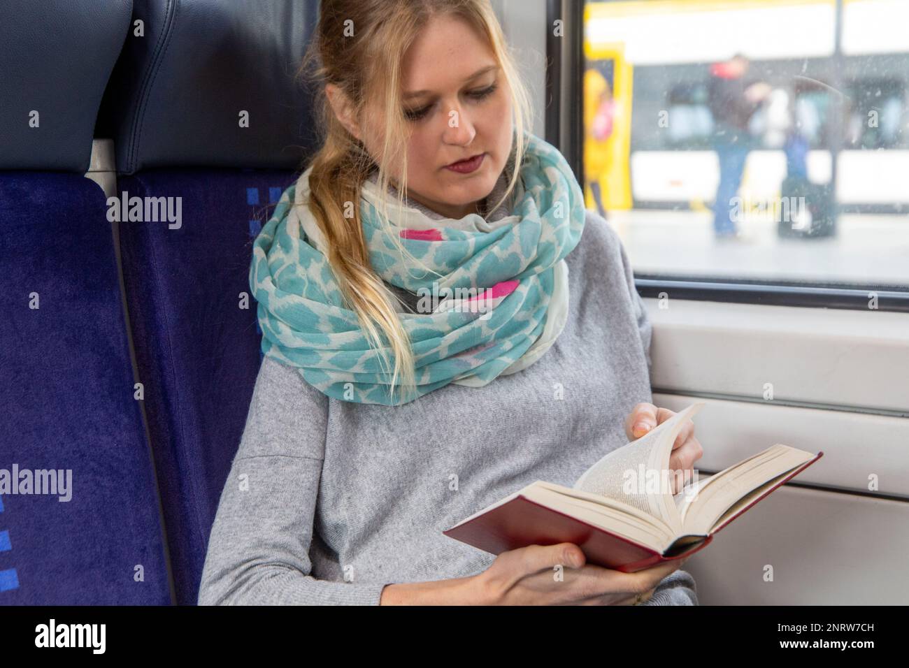 Young woman on train reading a book (Model released Stock Photo - Alamy