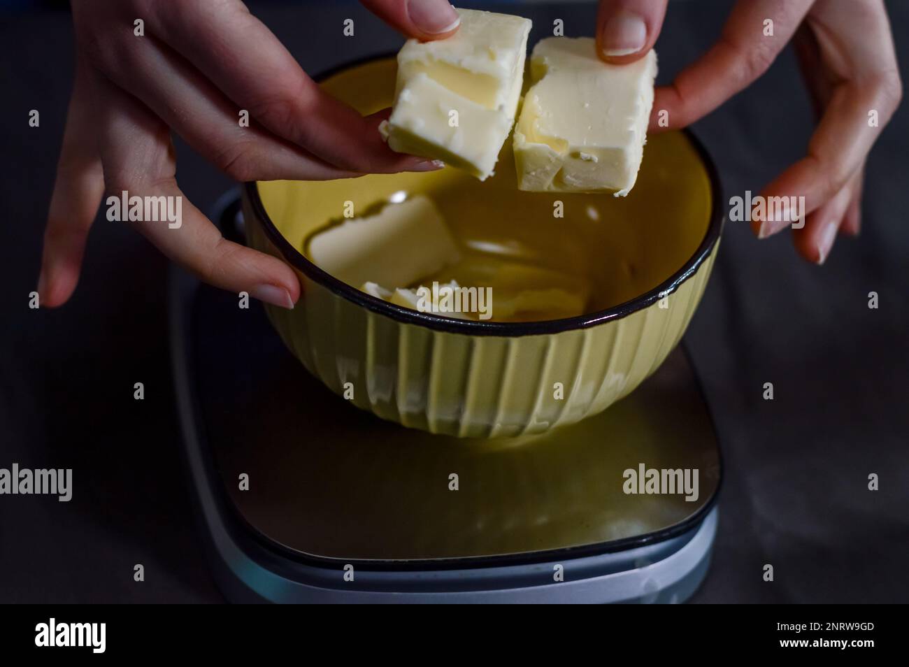 hands adding butter in a bowl to weigh it and make dessert recipe ...