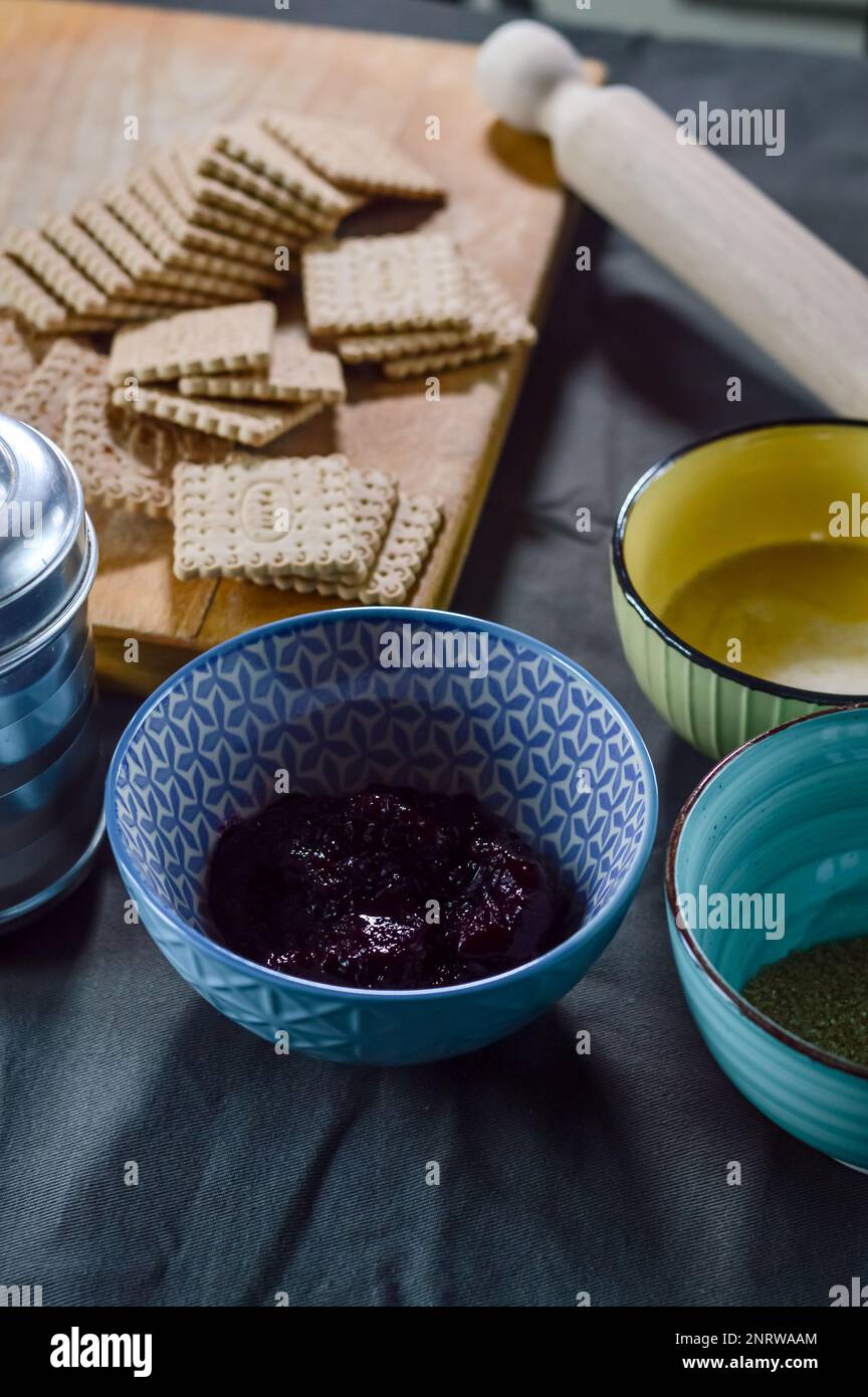 bowls with sugar, melted butter, jam and biscuits on a cutting board ...