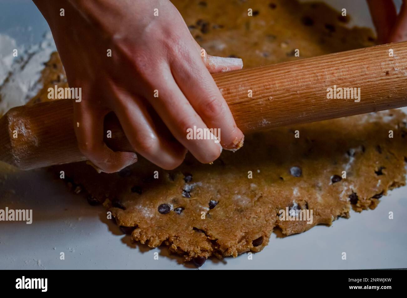 hands flattening a dough of flour, sugar, eggs and chocolate chips with ...