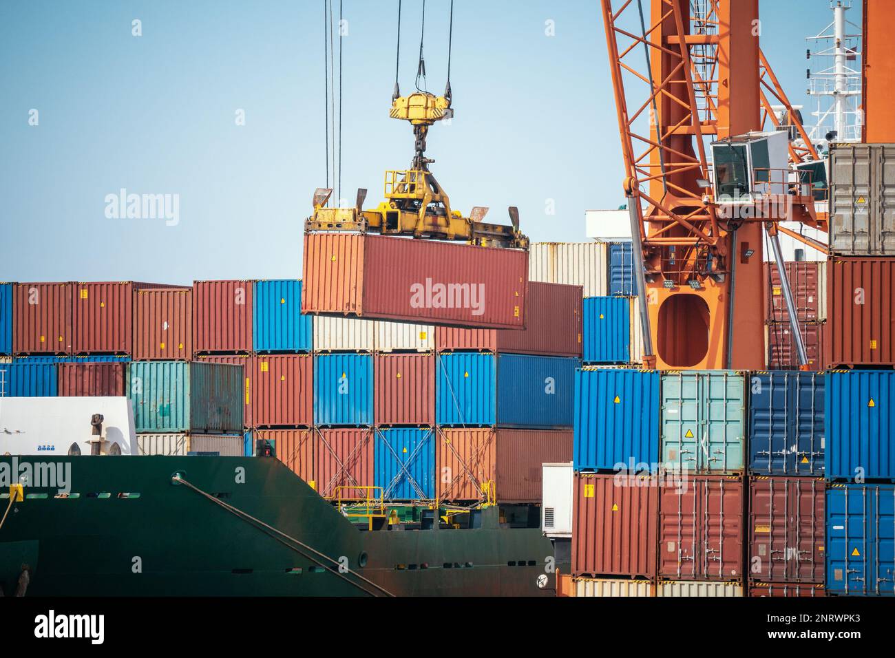 Harbor crane unloads containers from cargo ship at pier. Logistics, international trade ...