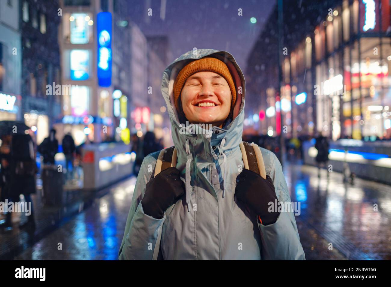 snowfall woman in a blue jacket and yellow hat christmas outside, city ...