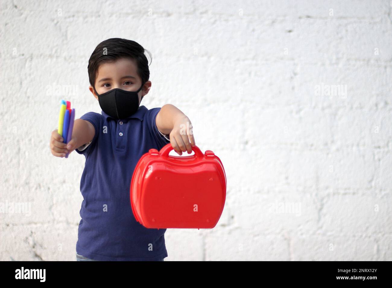 6-year-old boy with protective mask, lunch box and colors for back to ...