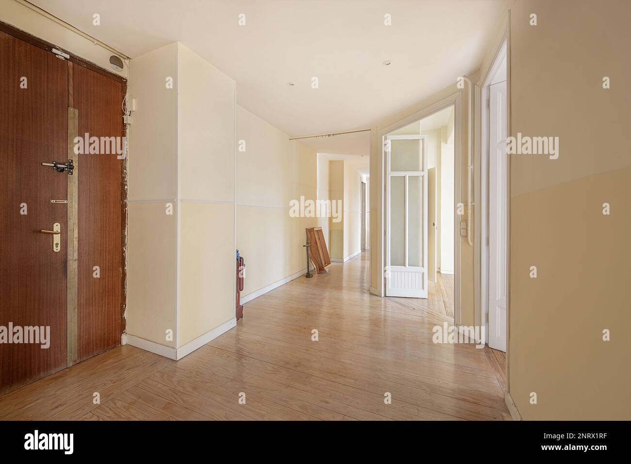 Spacious entrance hall of a house with a wooden access door with golden ...