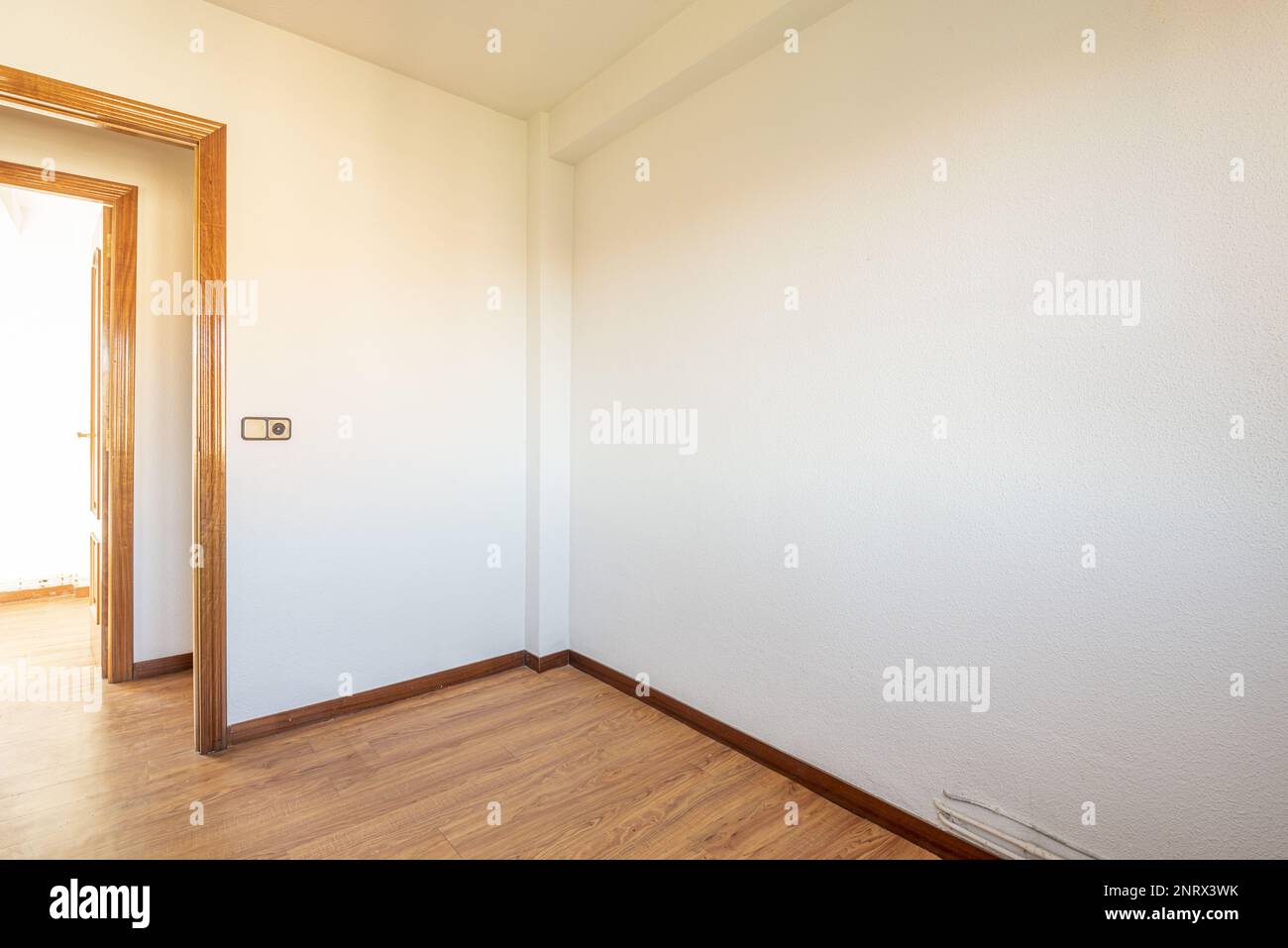 Small empty room with oak flooring, white walls with gotelet and access ...