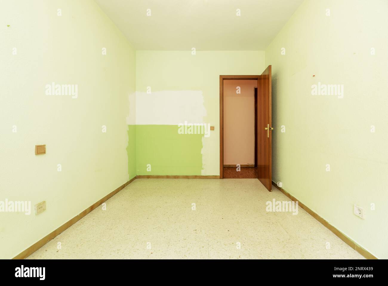 Small empty room with a light terrazzo floor, poorly painted walls and ...