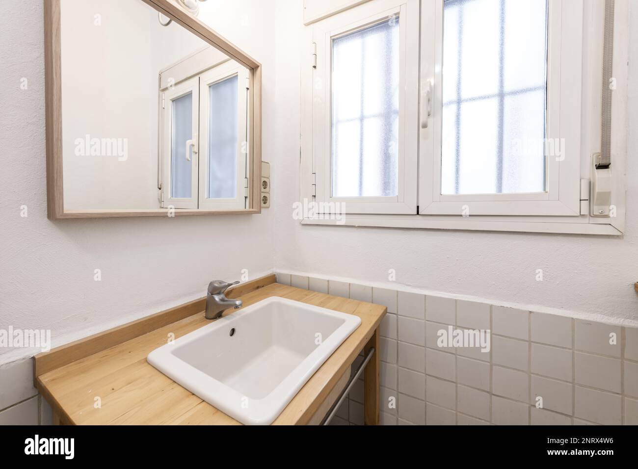 Small toilet with barred aluminum windows, wooden framed mirror and ...