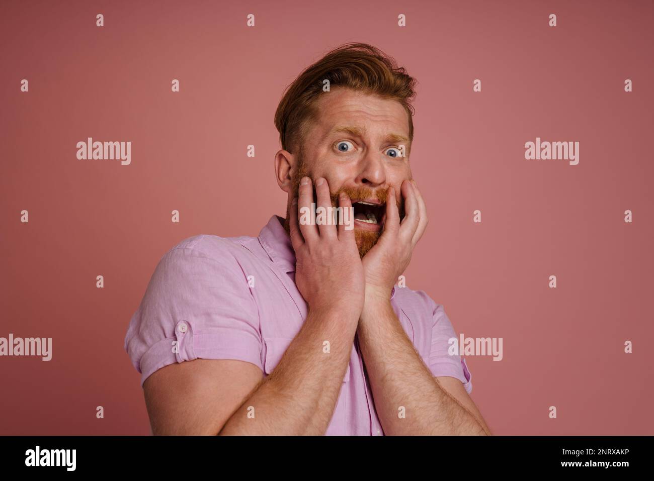 Ginger scared man holding his face while screaming at camera isolated ...