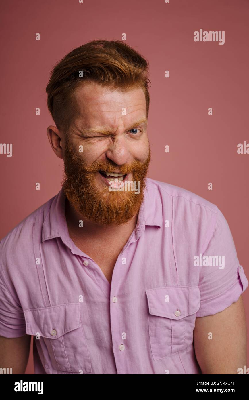 Ginger white man with beard winking and smiling at camera isolated over ...