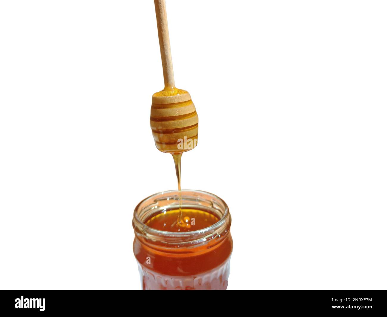 polyflora bee honey flowing into a jar from a wooden spoon. The concept ...